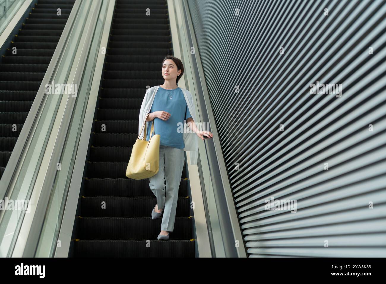Woman riding escalator Stock Photo - Alamy