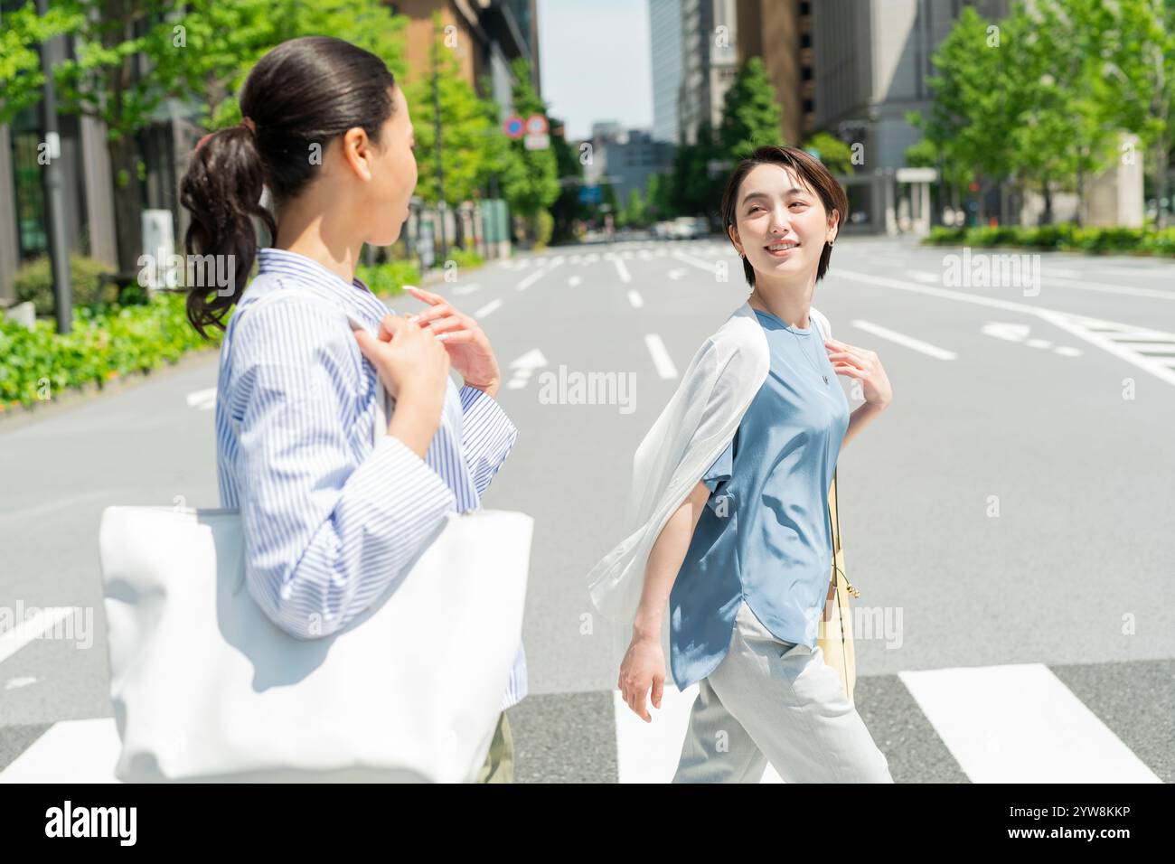 Two women crossing the pedestrian crossing Stock Photo - Alamy