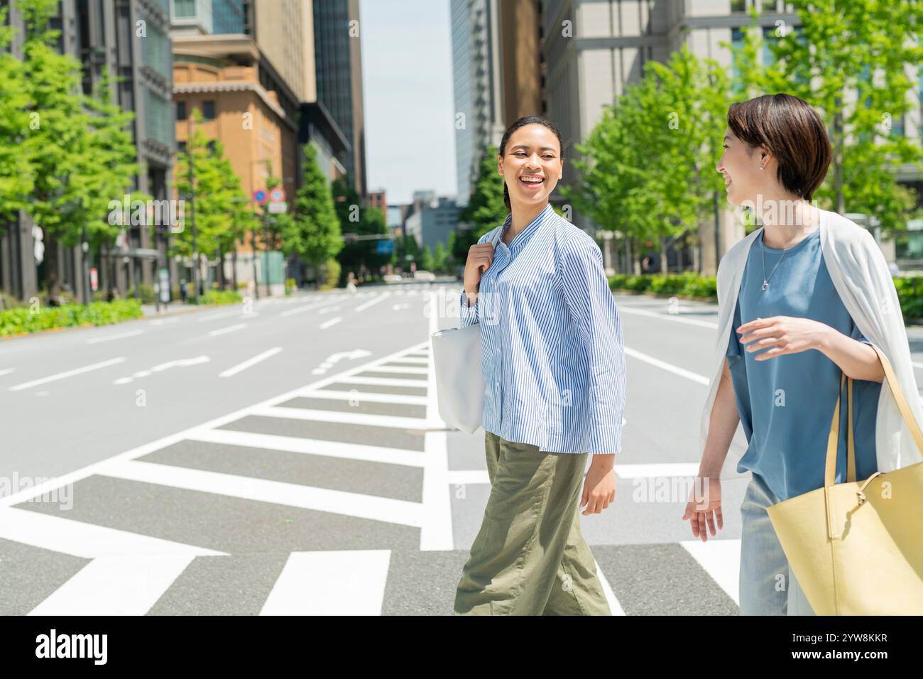 Two women crossing the pedestrian crossing Stock Photo - Alamy