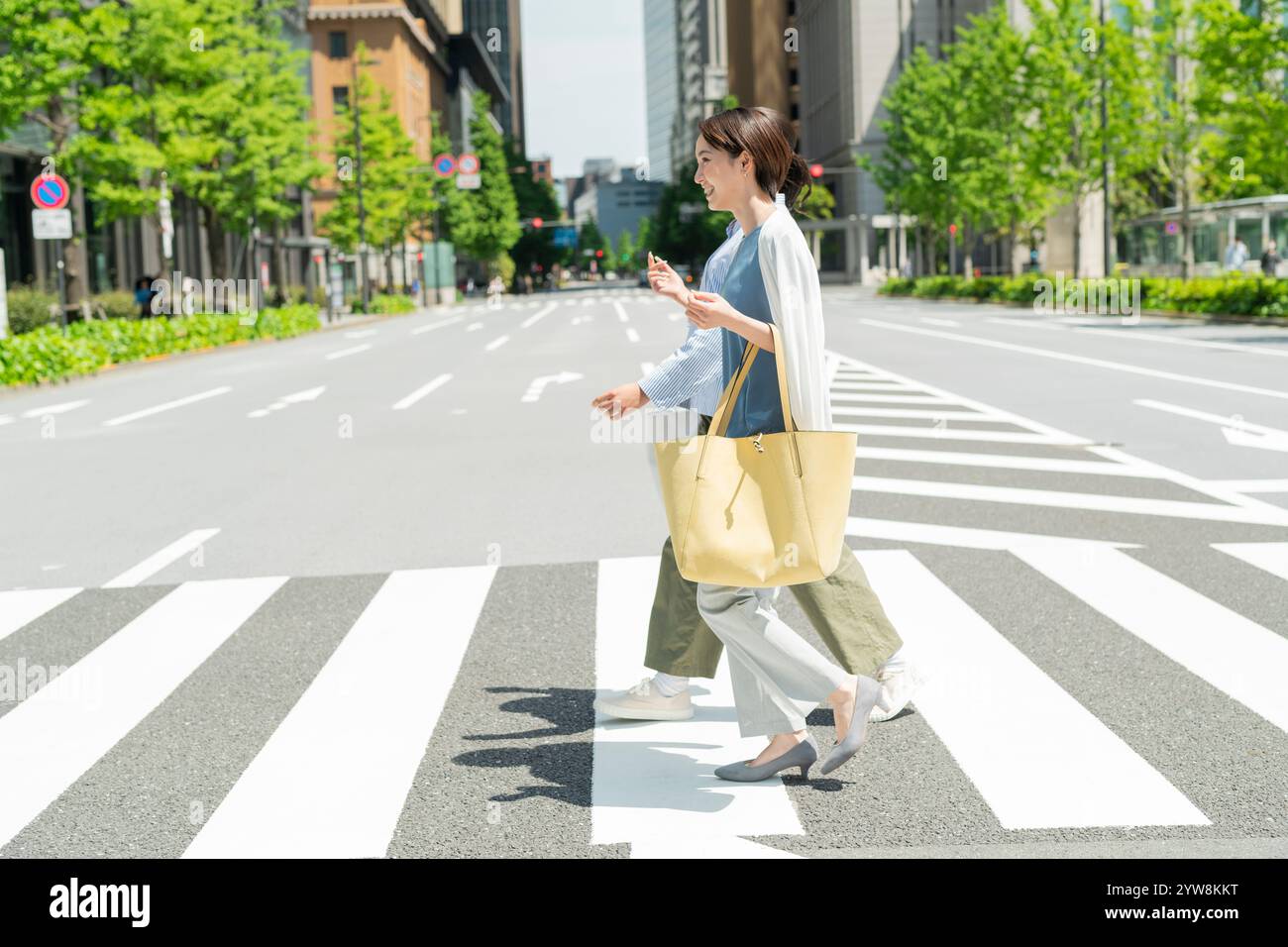 Two women crossing the pedestrian crossing Stock Photo - Alamy