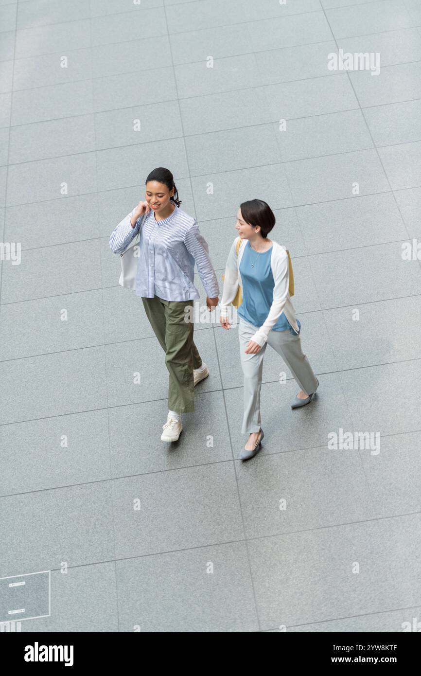 Two women walking inside a building Stock Photo - Alamy