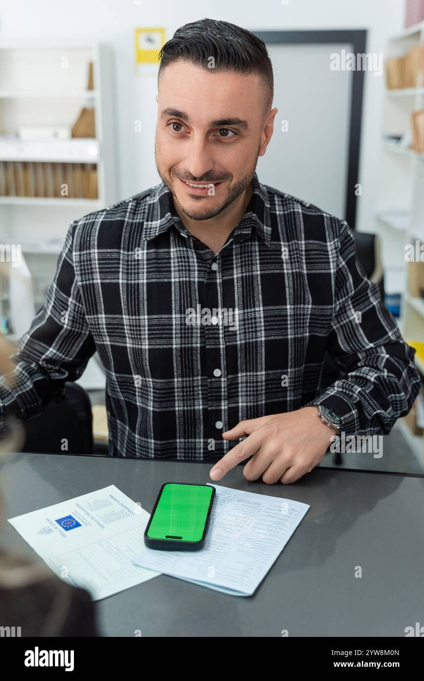 Office worker pointing at a smartphone with green screen chroma key ...