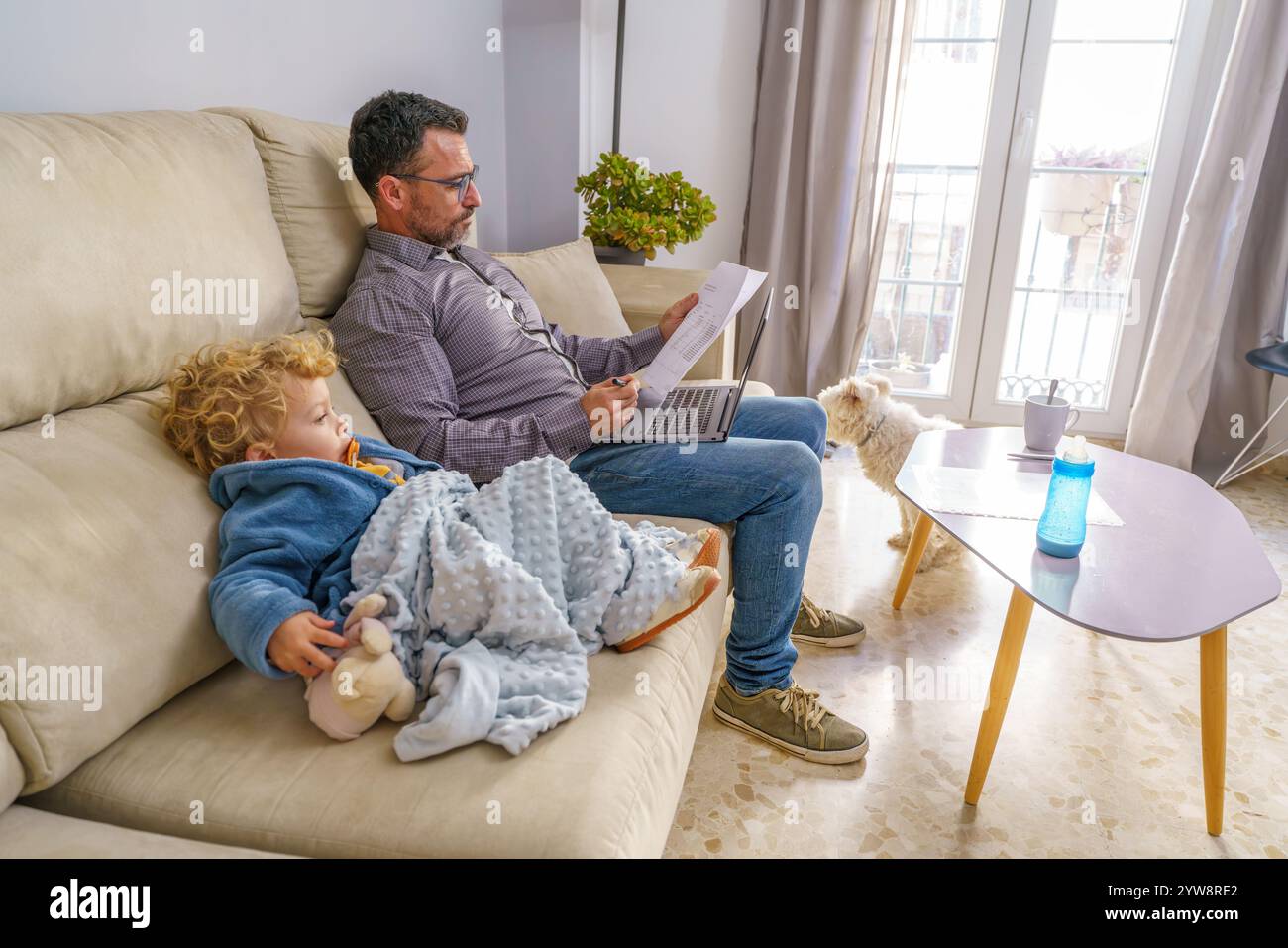 Businessman working remotely from home while caring for his sick ...
