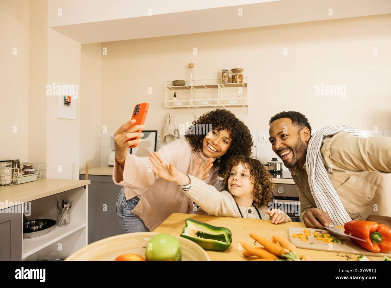 A joyful family during a video call in the kitchen. The parents and ...