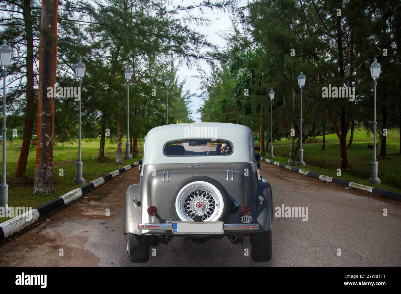 A classic vintage car cruising along a beautiful scenic park road ...