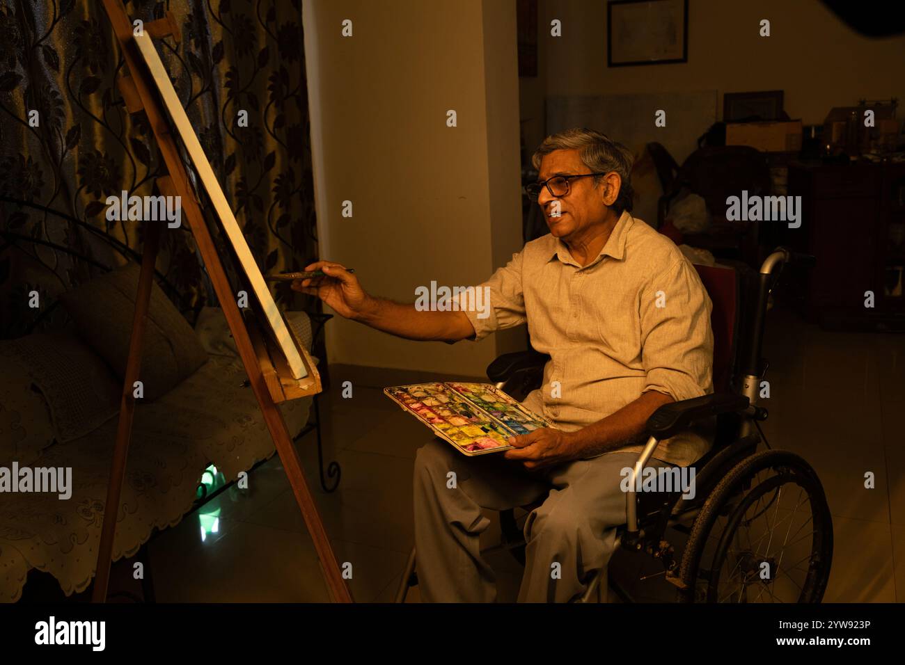 Indian creative senior disabled man or artist painting on canvas with a ...