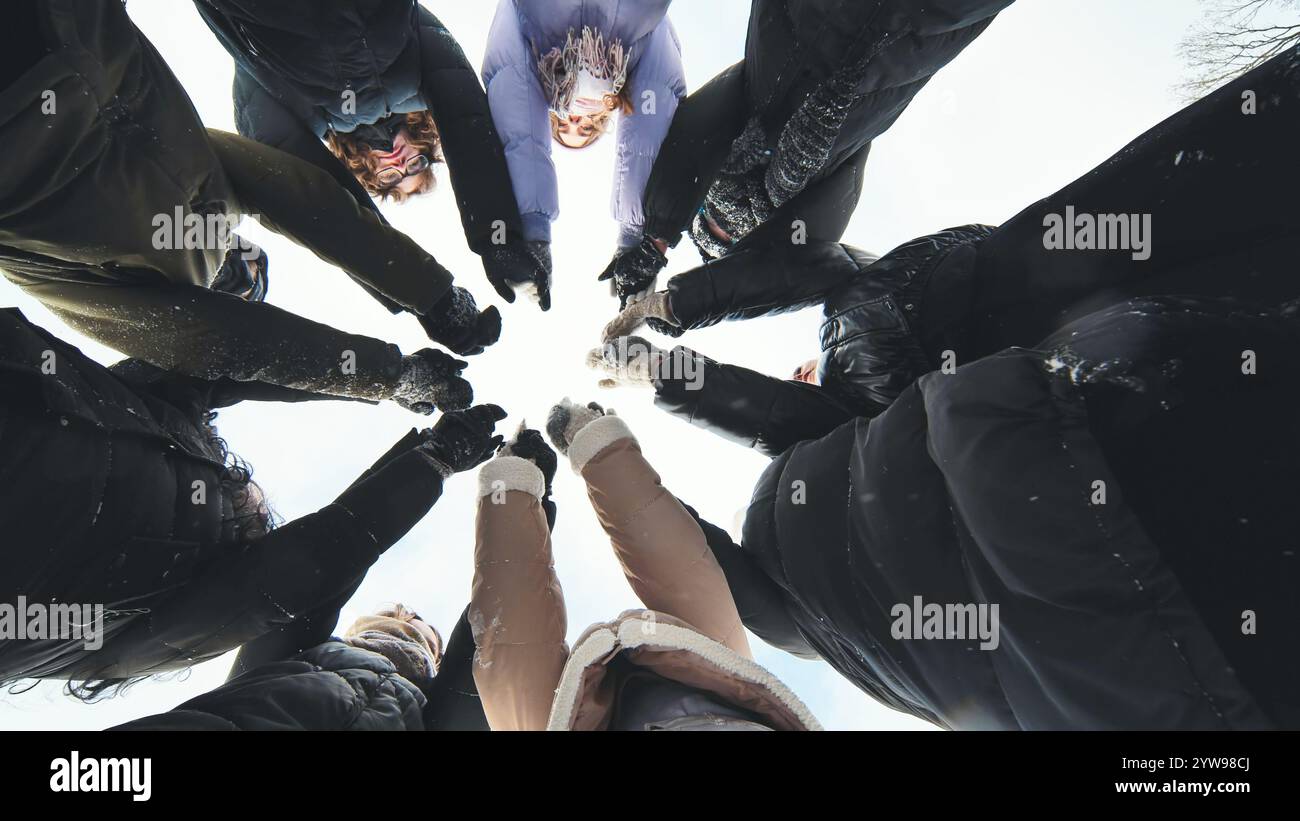 Schoolgirls in winter attire creating a circle with their hands joined ...