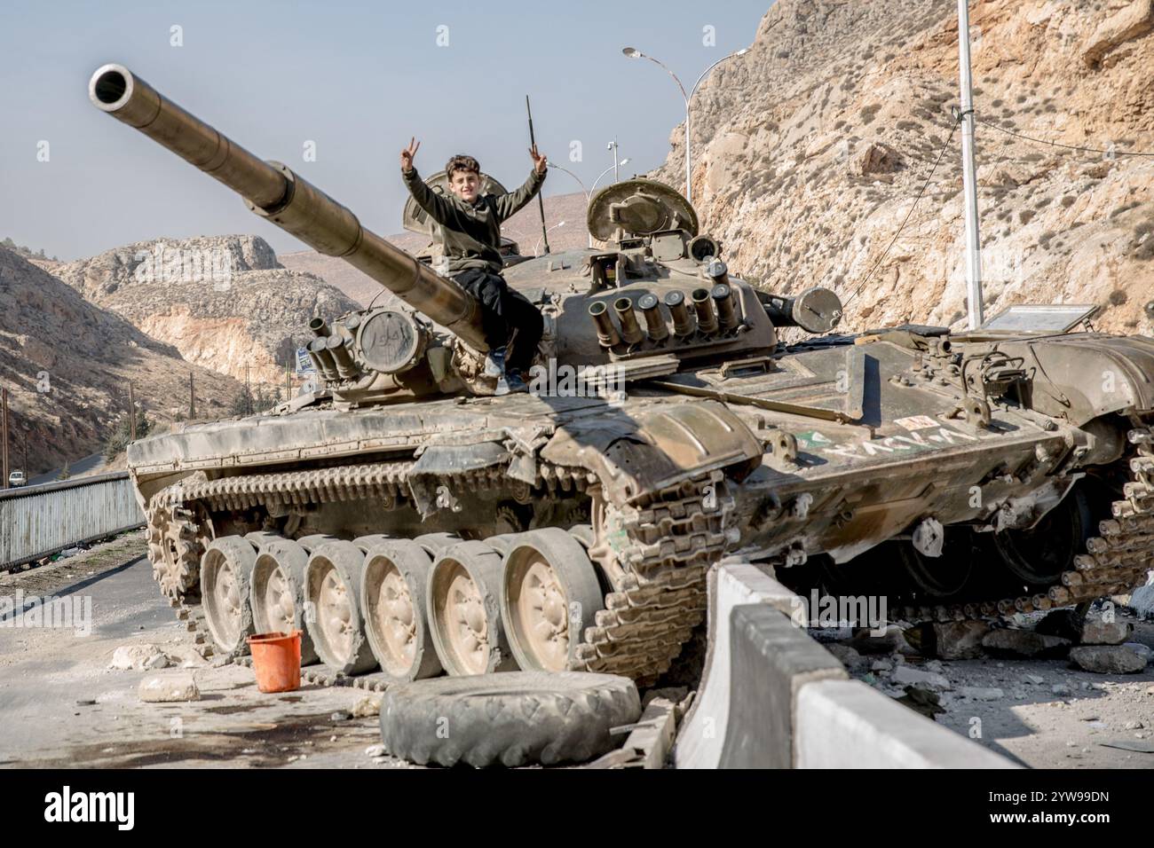 A boy flashes the "v" sign while sitting on a tank in Syria close to ...