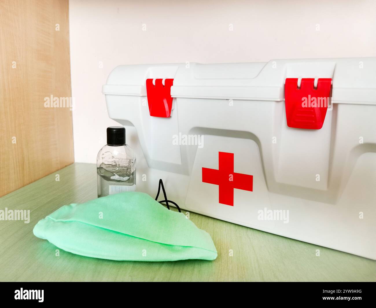First aid kit, surgical mask and hand sanitizer on table Stock Photo ...