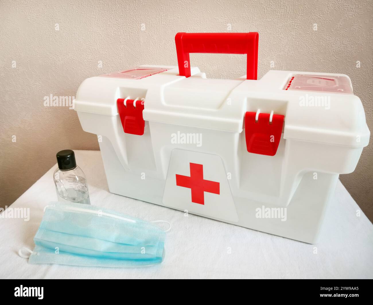 First aid kit with red cross, surgical mask and hand sanitizer on white ...