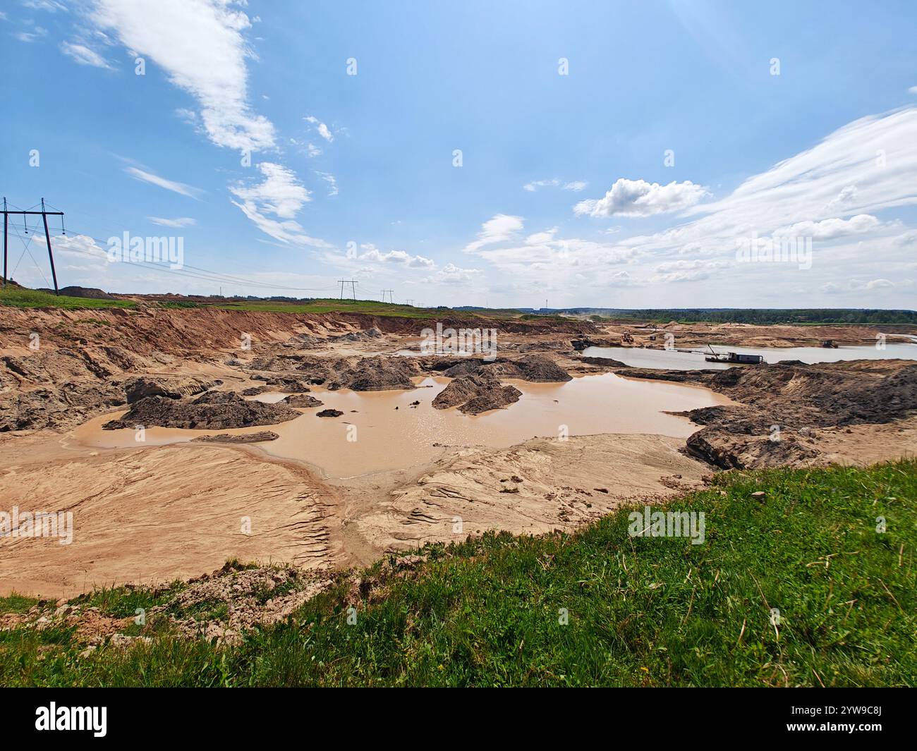 Large excavation area features muddy water pools and rocky terrain ...