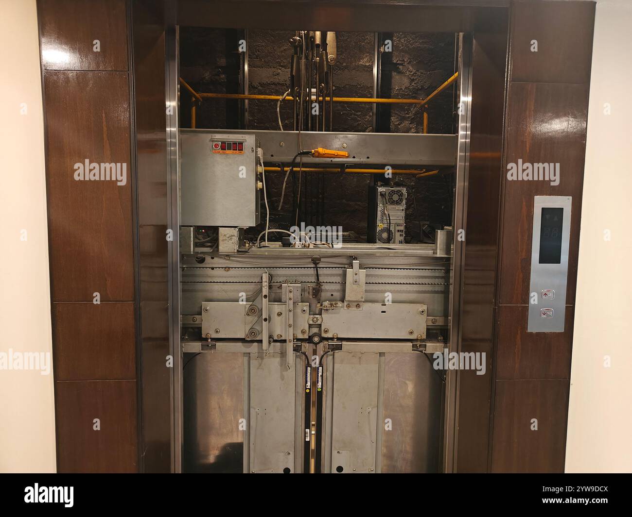 Maintenance work reveals the inner machinery of a sleek elevator in a ...
