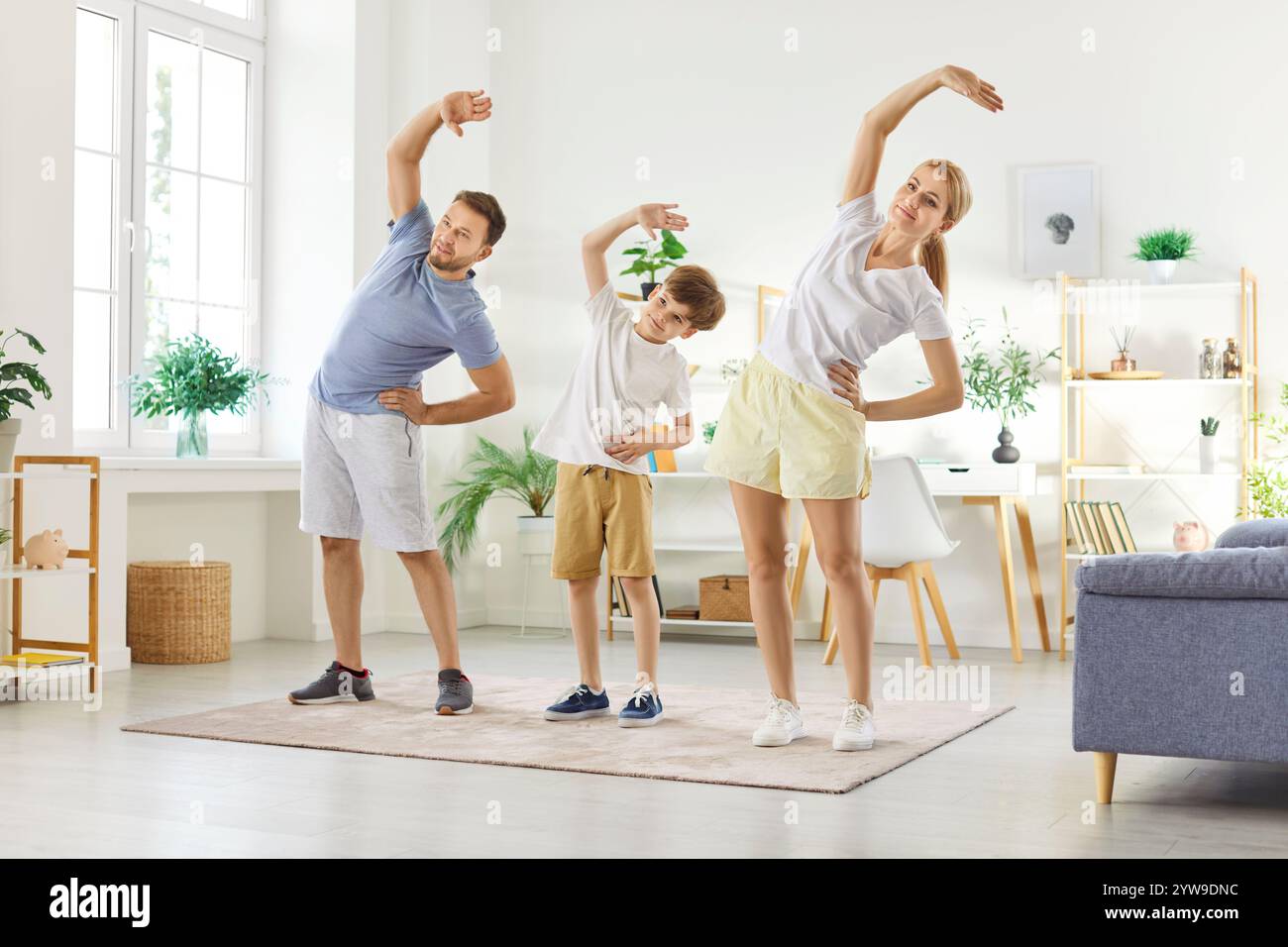 Sporty happy active young family doing morning sport training side bend ...