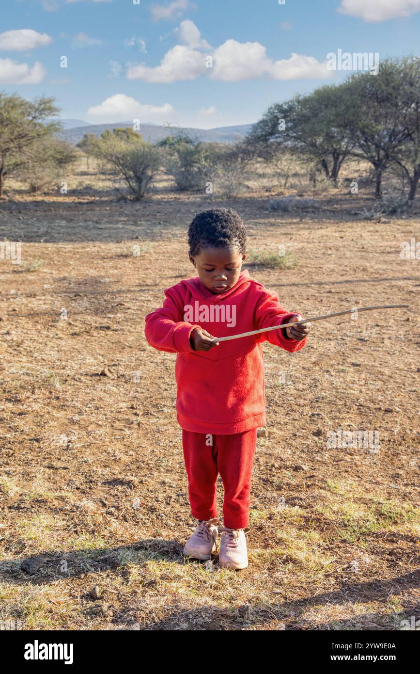 village portrait of african child playing by a stick outdoors, tree and ...
