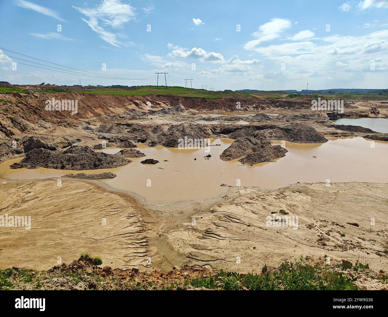 Large excavation area features muddy water pools and rocky terrain ...