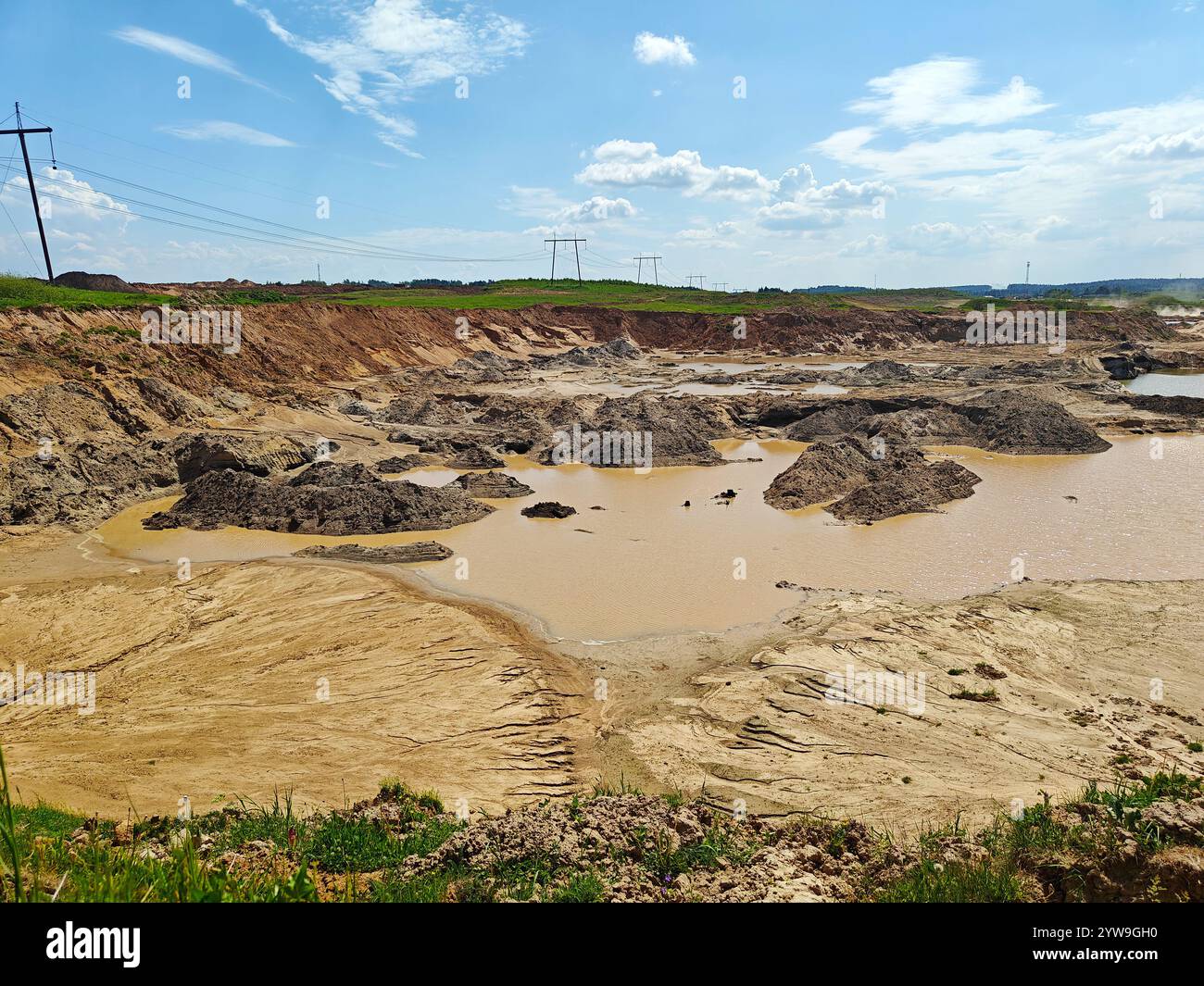 Large excavation area features muddy water pools and rocky terrain ...