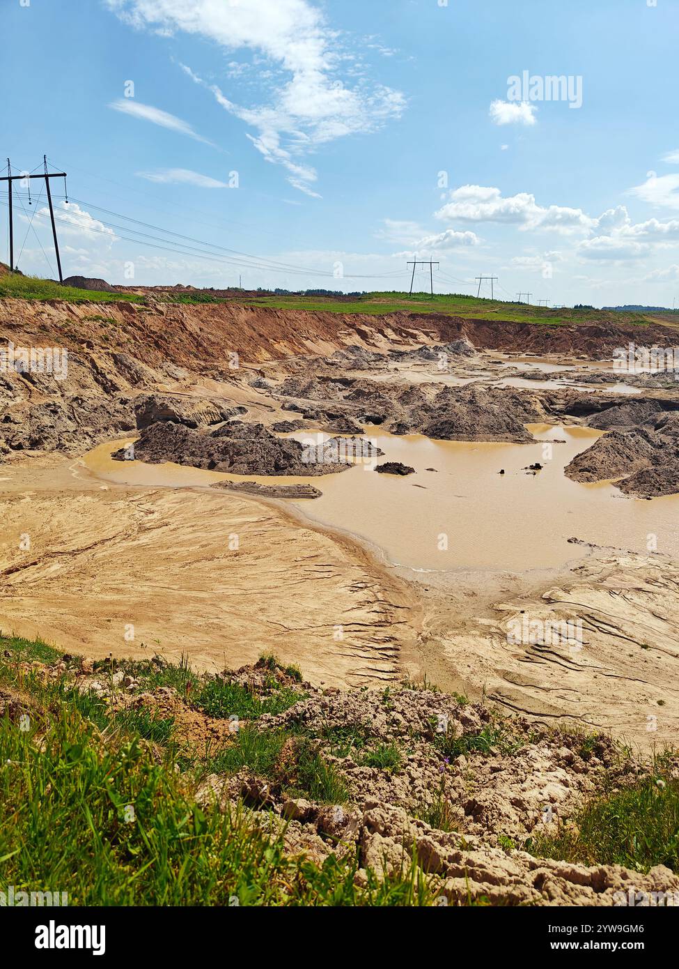 Large excavation area features muddy water pools and rocky terrain ...