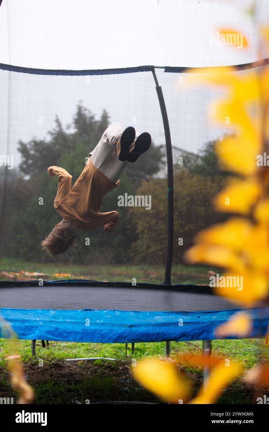 Boy practicing backflip on trampoline during a cloudy autumn day Stock ...