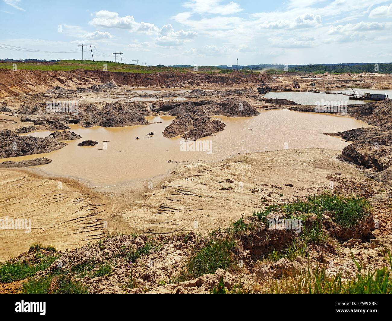 Large excavation area features muddy water pools and rocky terrain ...