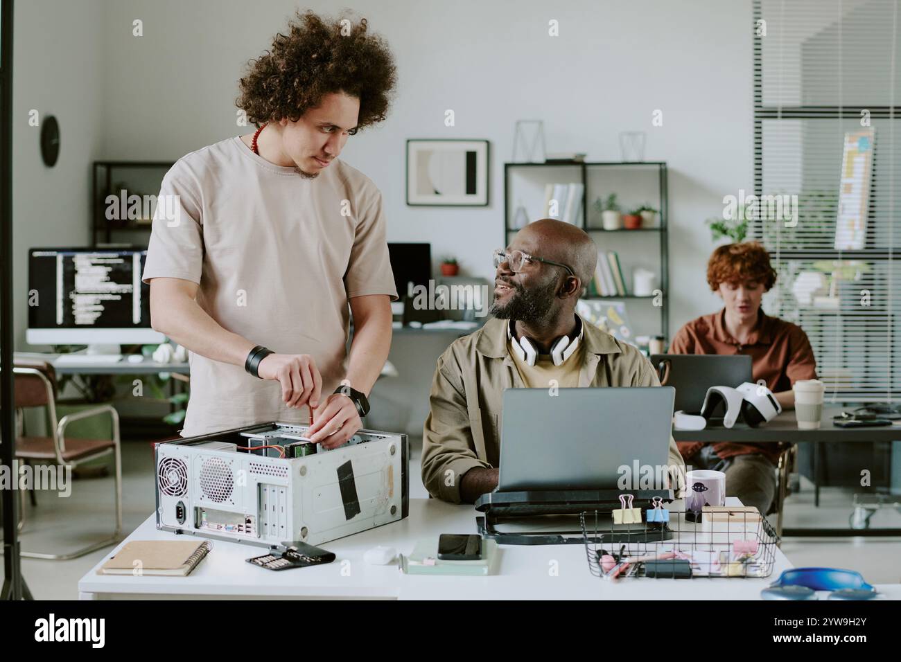 African American man interacting with young adult coworker repairing ...