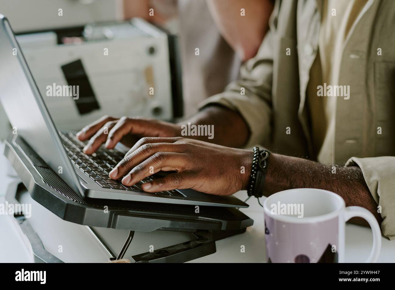 Medium close up of unrecognizable male hands typing on keyboard of laptop on cooling pad Stock ...