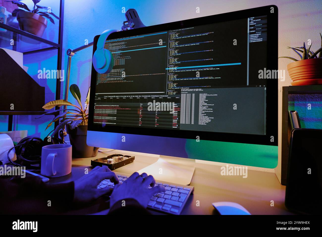 Medium close up of monitor with codes and headphones on desk ...