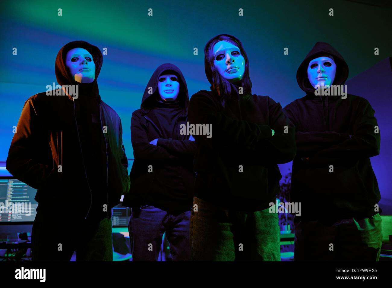 Low angle portrait of hacker group wearing black hoodie and white mask ...