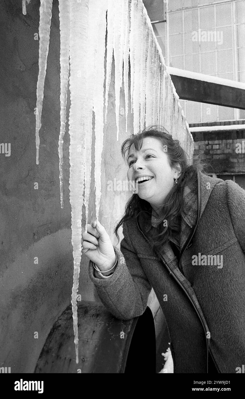 1987, January, cold weather, woman touching a long icicle on side of a ...