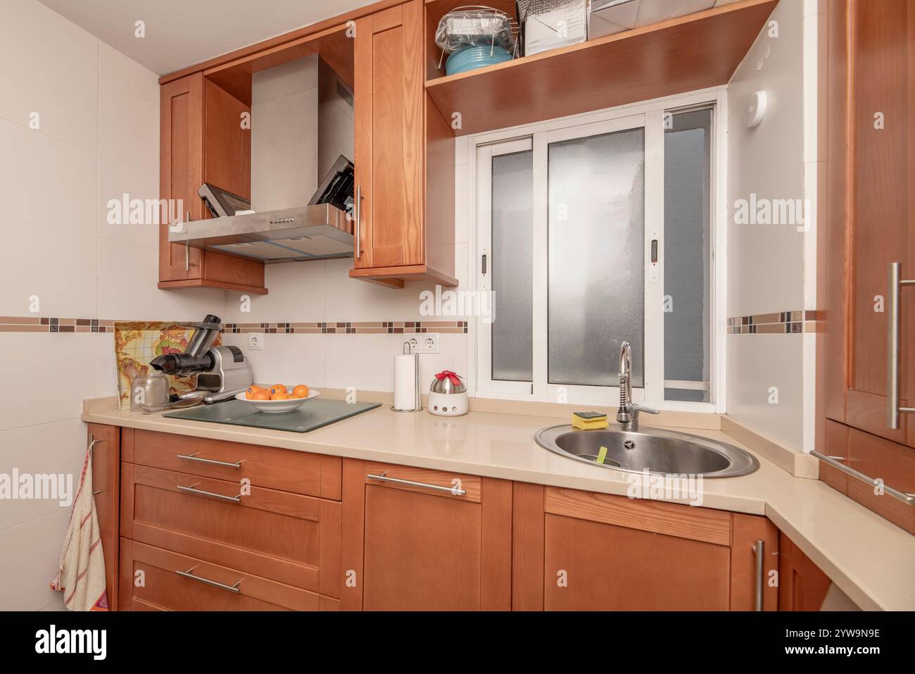 L-shaped fitted kitchen with cream stone effect worktop, sliding window ...