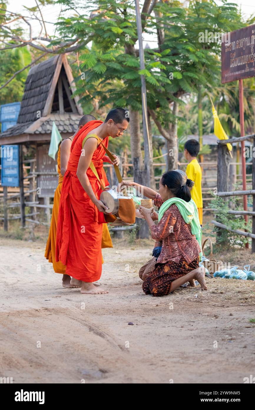 Local women giving rice to young buddhist monks in early morning on Don ...