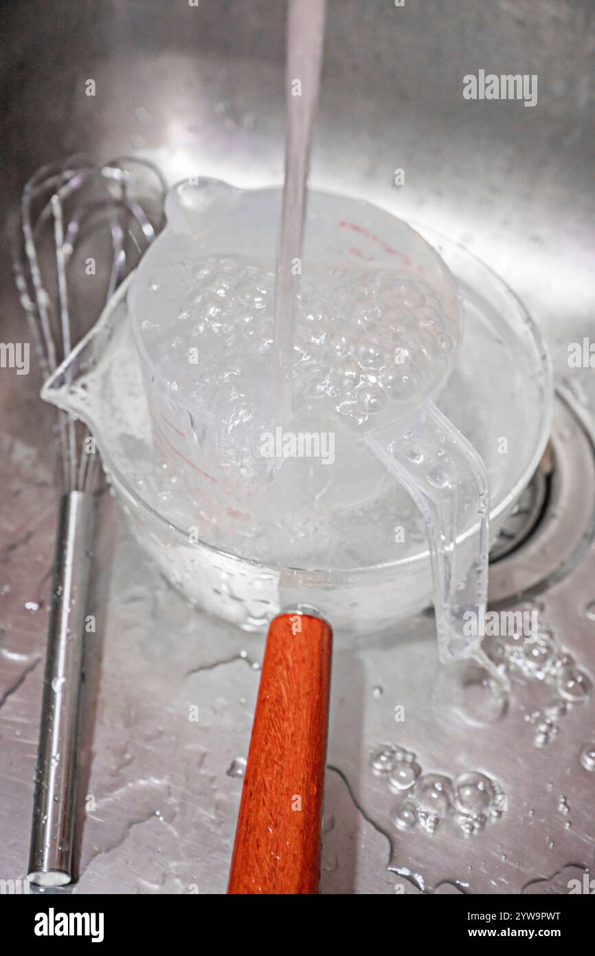 washing kitchen utensils in a stainless steel sink Stock Photo - Alamy