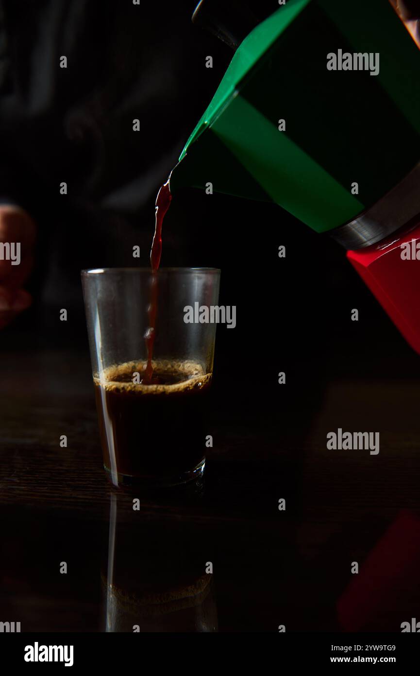 A rich espresso stream flows from a colorful stovetop coffee maker into ...