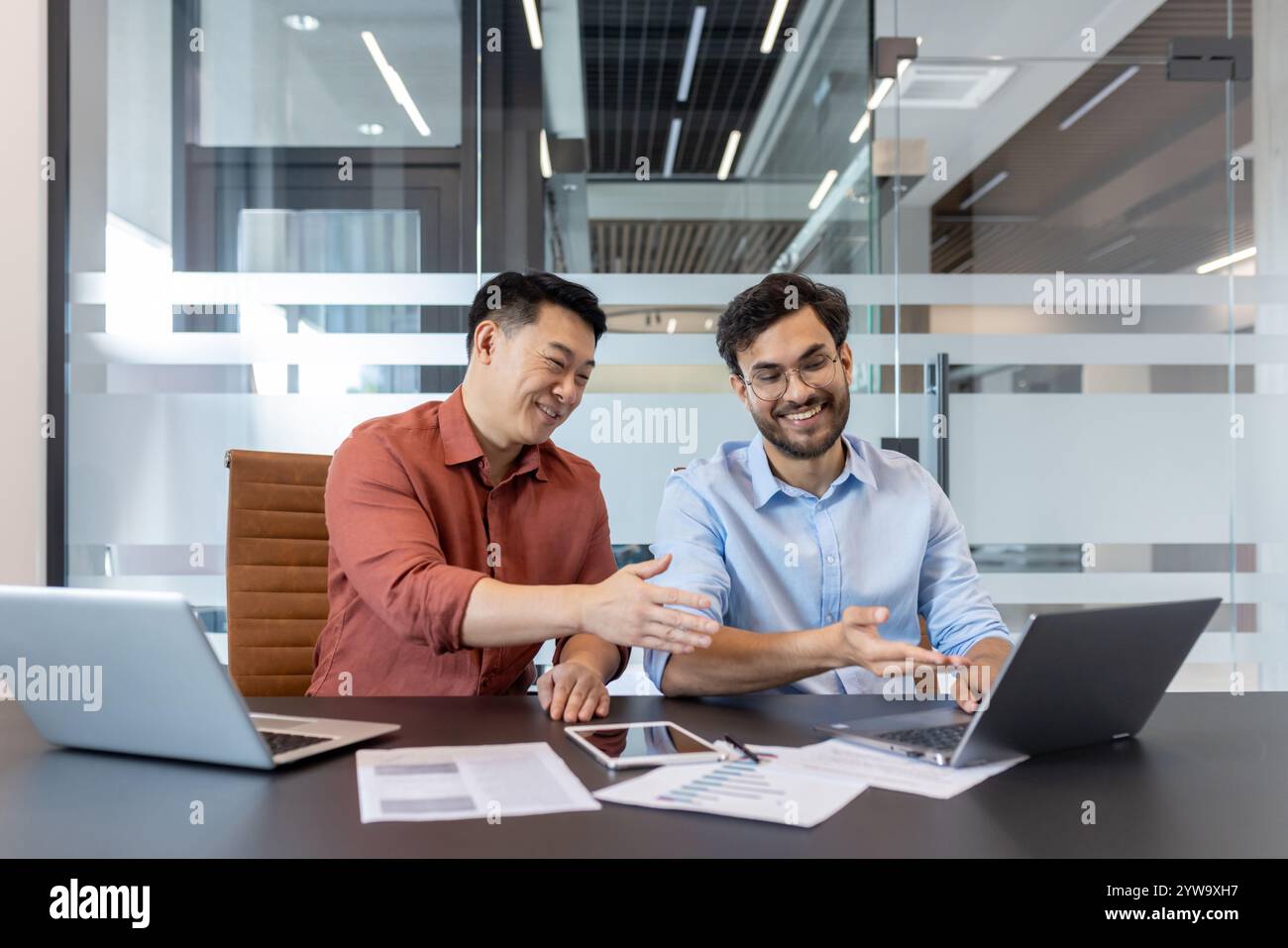 Two male colleagues are engaging in a discussion while working on ...