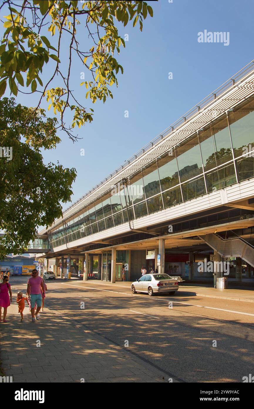 Modern railway station with glass facade, surrounded by trees, on a ...