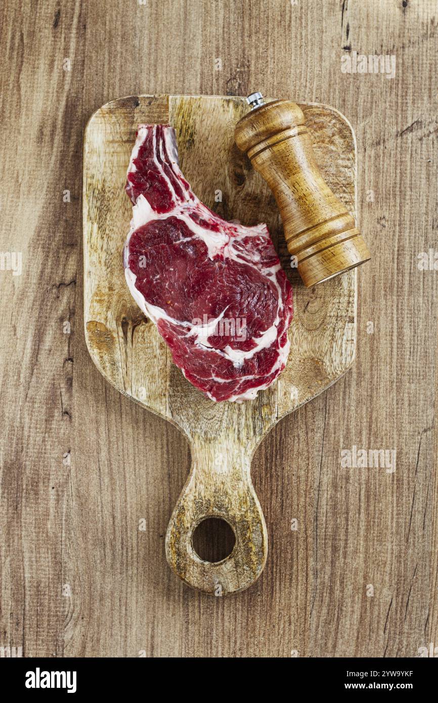Raw rib eye steak, cowboy steak, on a wooden chopping board, top view ...