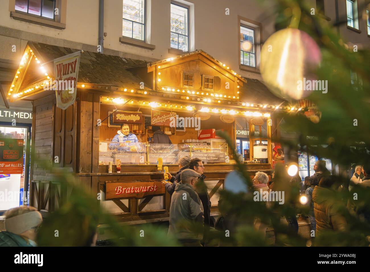 Christmas market with illuminated wooden hut and people in a cosy ...