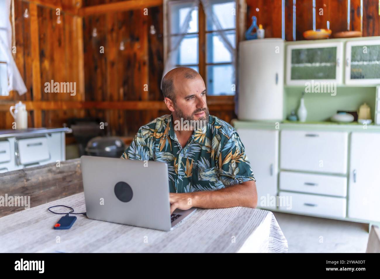 Digital nomad working on laptop in a rustic wooden cabin, embracing the ...