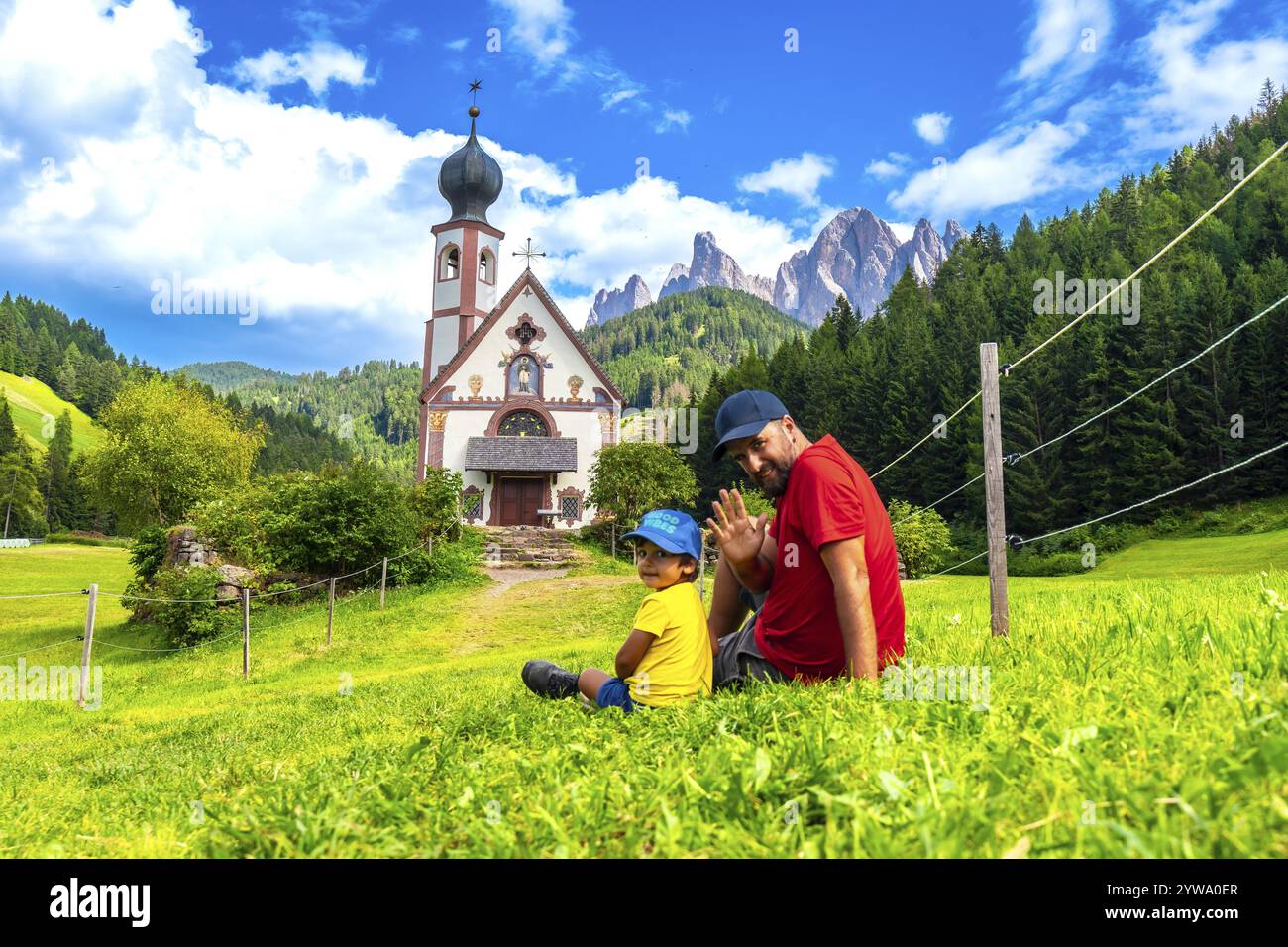 Father and son waving while sitting on grass in front of st. Magdalena ...