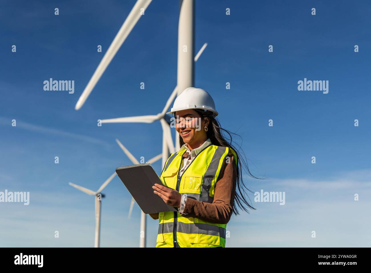 Smiling latin american female engineer wearing safety vest and helmet ...