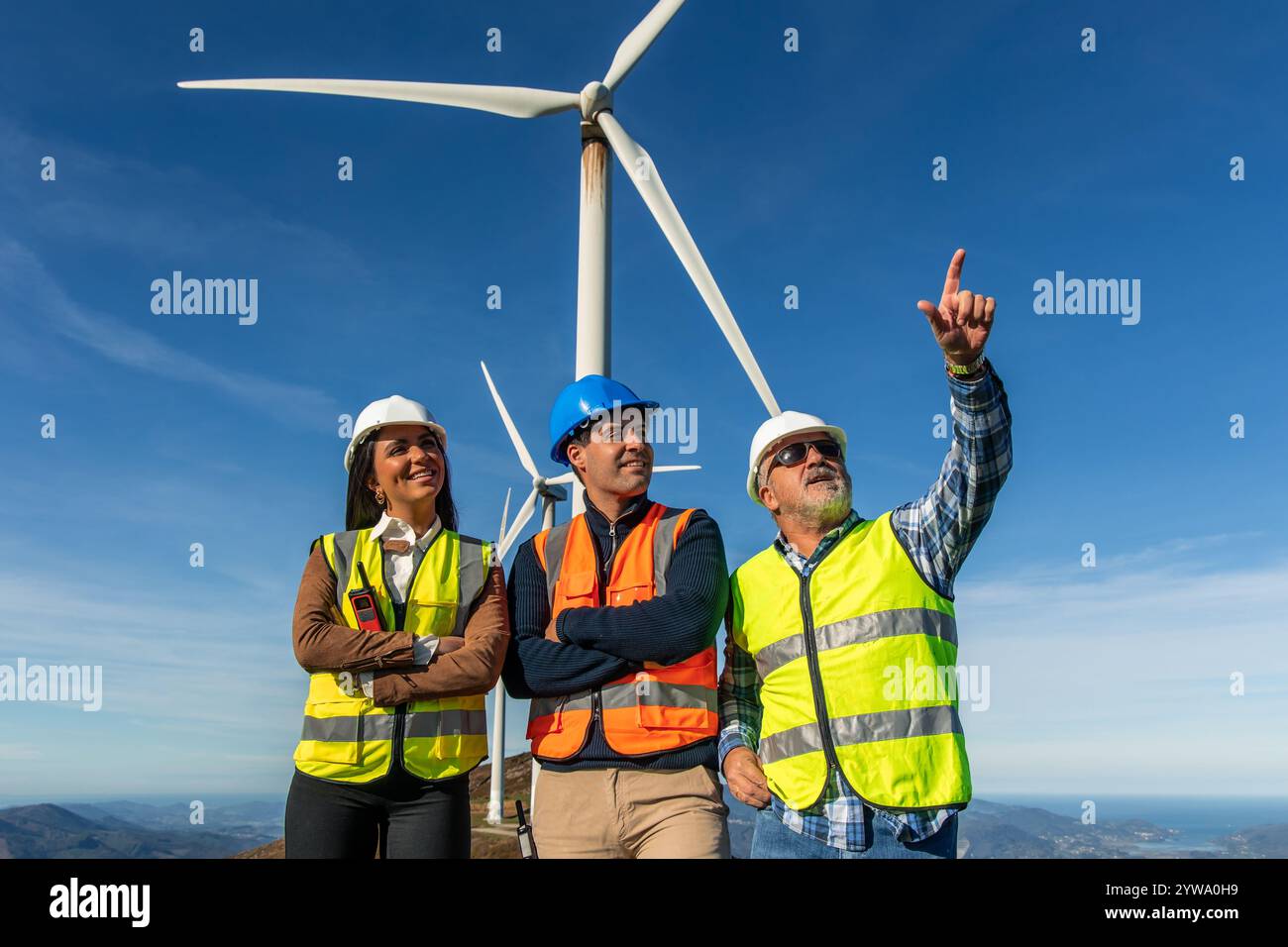 Three multiethnic engineers wearing safety vests and helmets are ...