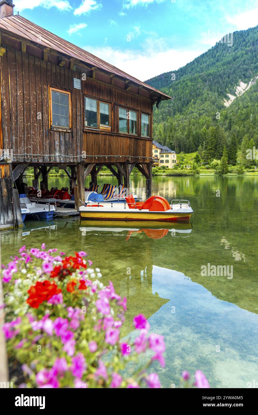 Colorful pedal boats dock under a traditional wooden boathouse on the ...
