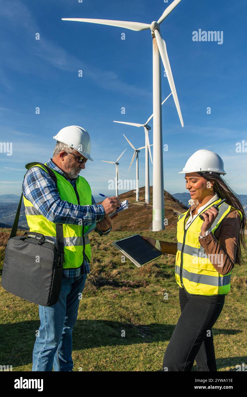 Two engineers wearing safety vests and helmets are discussing ...