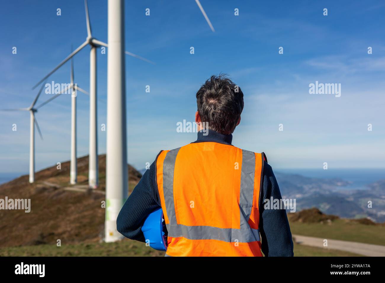 latin Engineer wearing a safety vest and holding a helmet observes a ...