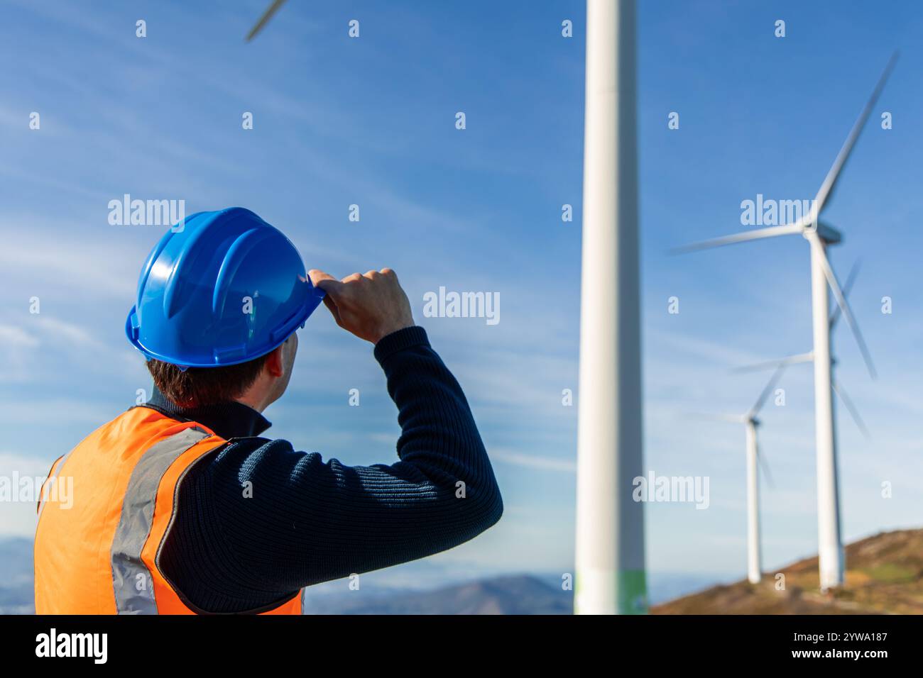 latin Engineer wearing an orange safety vest and blue helmet is holding ...