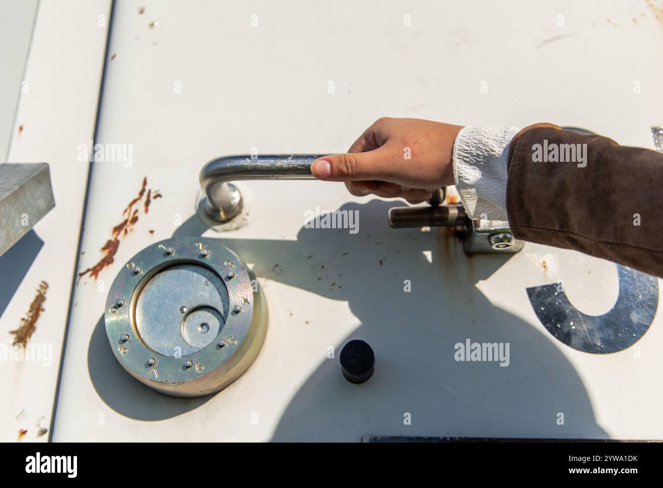 Technician's hand opening the hatch of a large industrial tank for ...