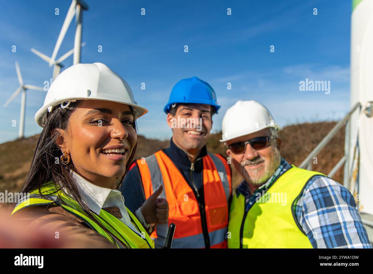 Three multiethnic smiling engineers wearing safety helmets and vests ...