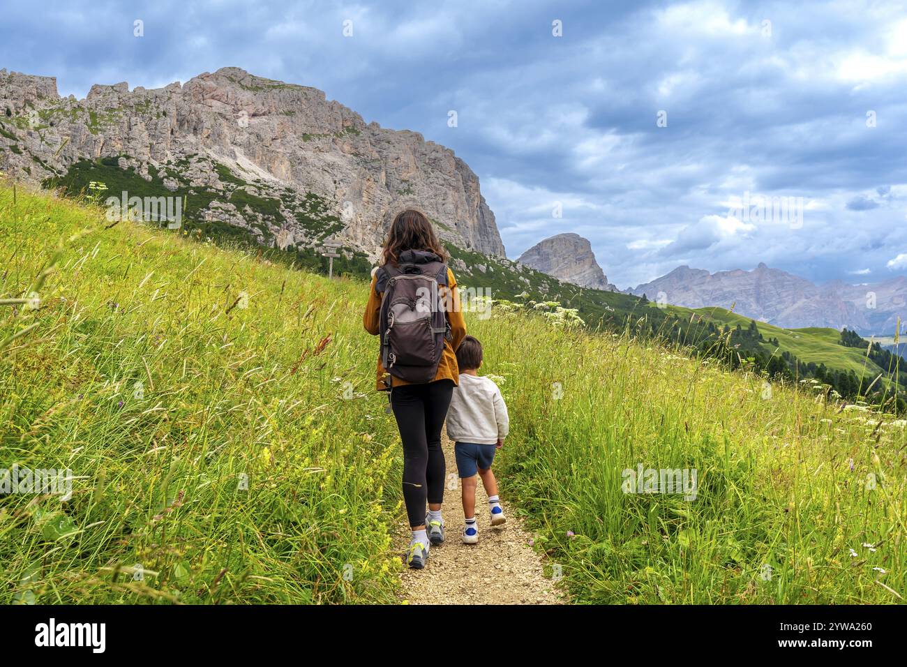 Mother and son walking on a path surrounded by lush green grass ...