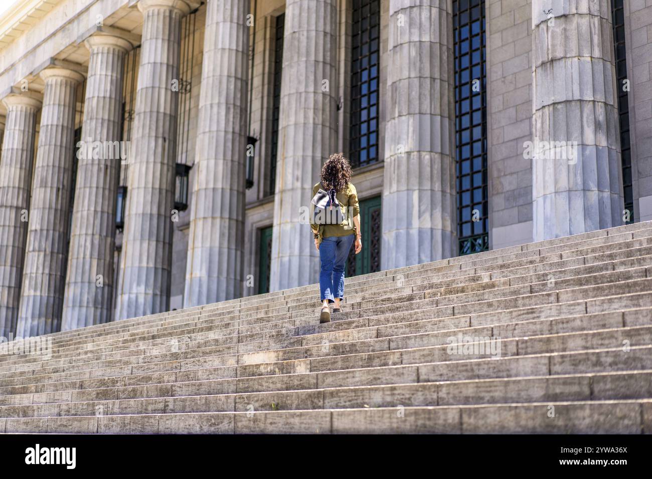 Confident mid-adult student walking up university steps Stock Photo - Alamy