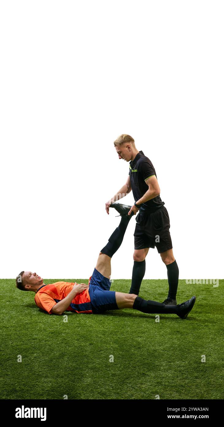Referee helping man, soccer player lying on floor with injured leg ...