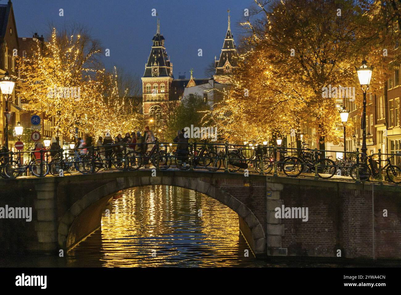 Bicycles parked on a night-lit bridge over a canal, Amsterdam ...